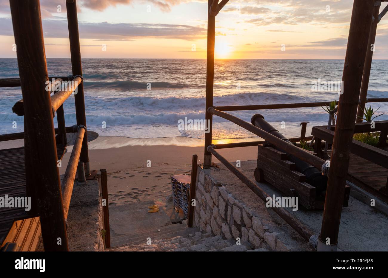 Stone stairs leading to a sandy beach with a beautiful sunset view ...
