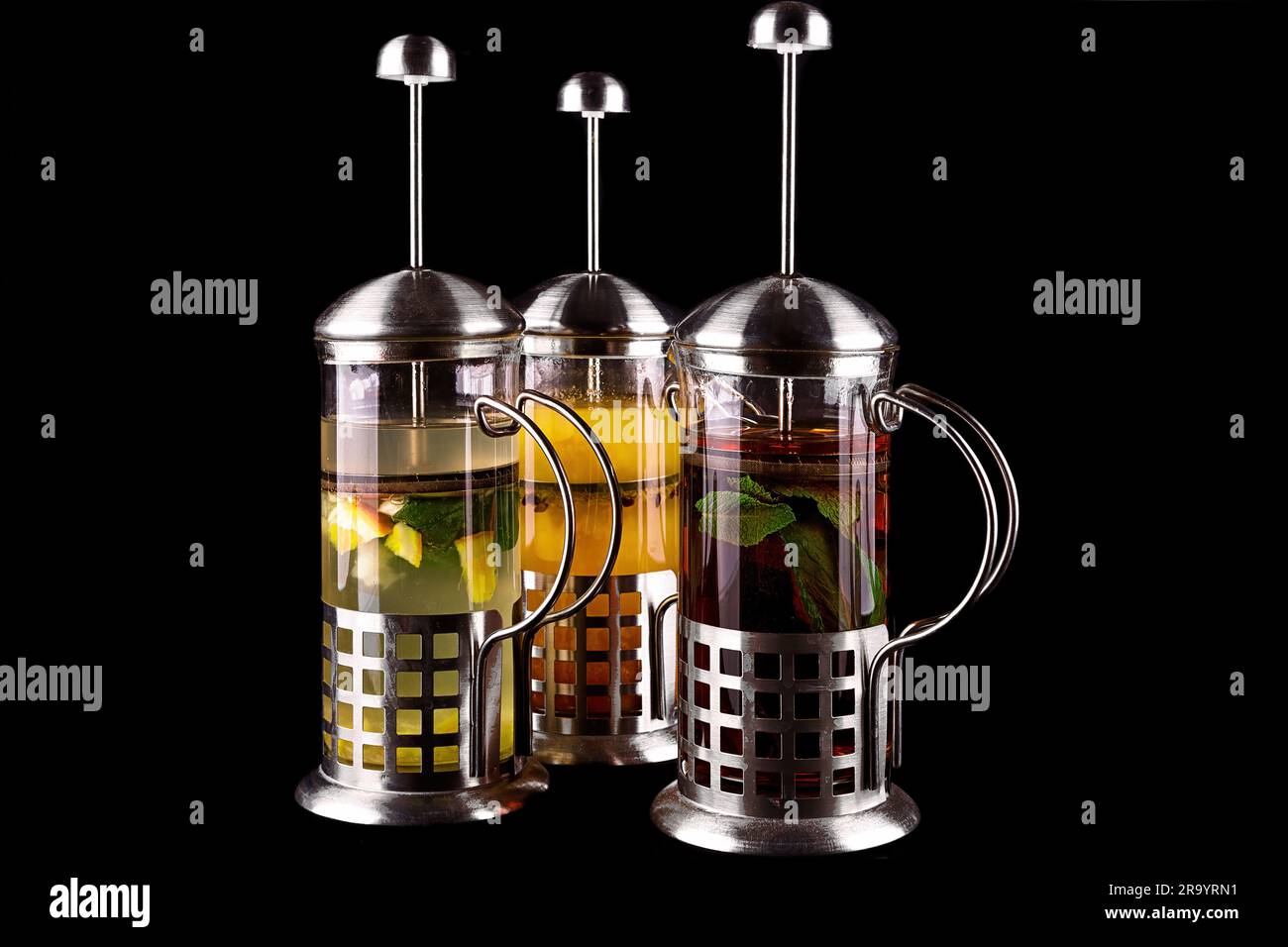 Three types of tea with mint, sea buckthorn and lemon in glass teapots ...