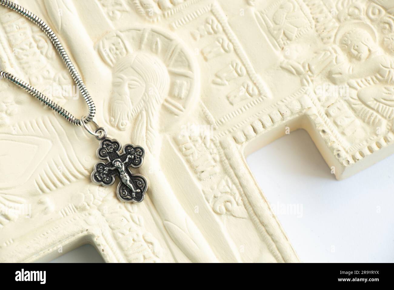 christian plaster cross and silver cross on chains on a white ...