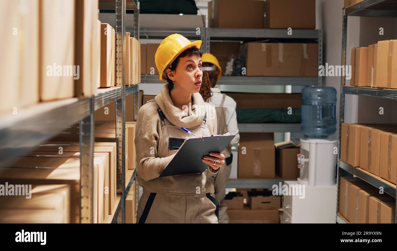 Female employee checking list of goods on papers, using files to do ...