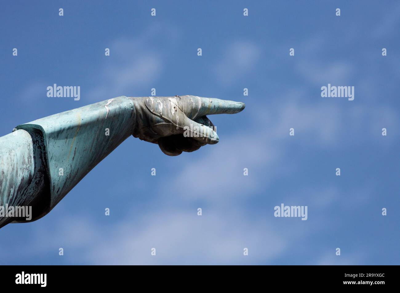 Close-up of hand pointing index finger against blue sky. Statue of Karl ...