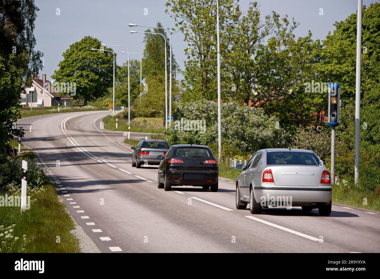 Cars and speed camera on road along trees Stock Photo - Alamy