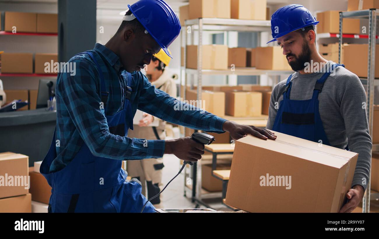 Diverse employees examining packs of goods in depot space, scanning ...