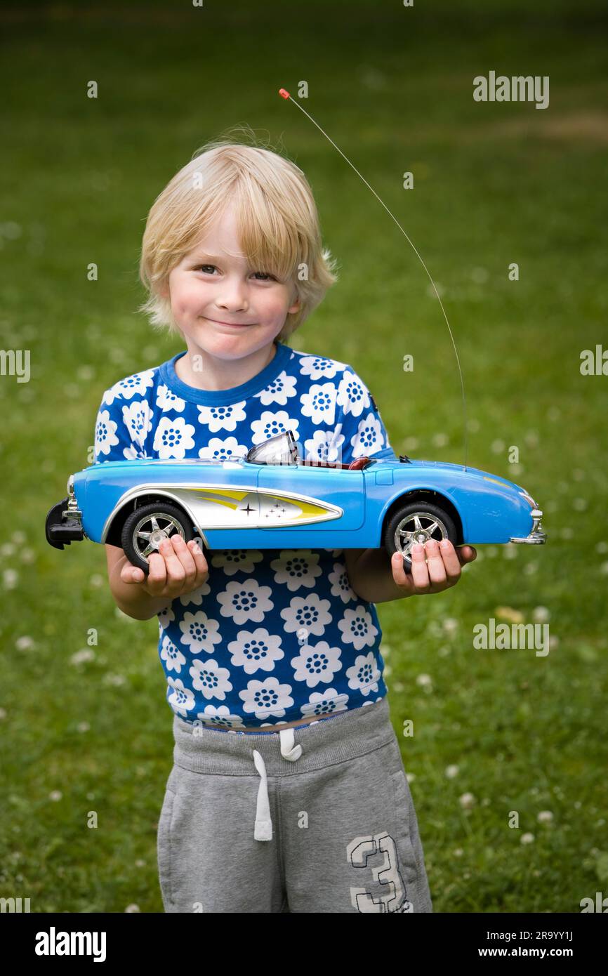 Portrait of a cute and happy little boy holding a remote controlled car ...
