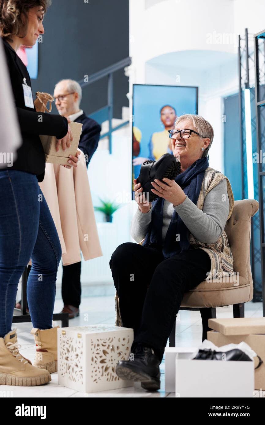 Senior woman trying fashionable black shoes, shopping for formal wear ...