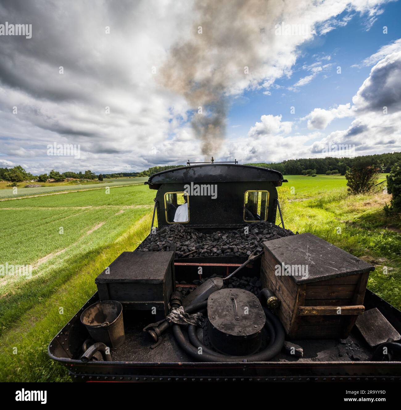 Close-up of steam locomotive from behind through agricultural fields ...