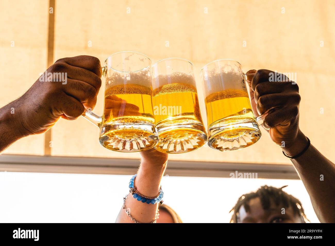 small group of young adult multiethnic friends toasting with three mugs ...