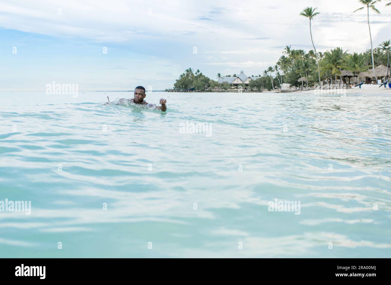 A young black male swimming in a tropical sea with bright blue water ...