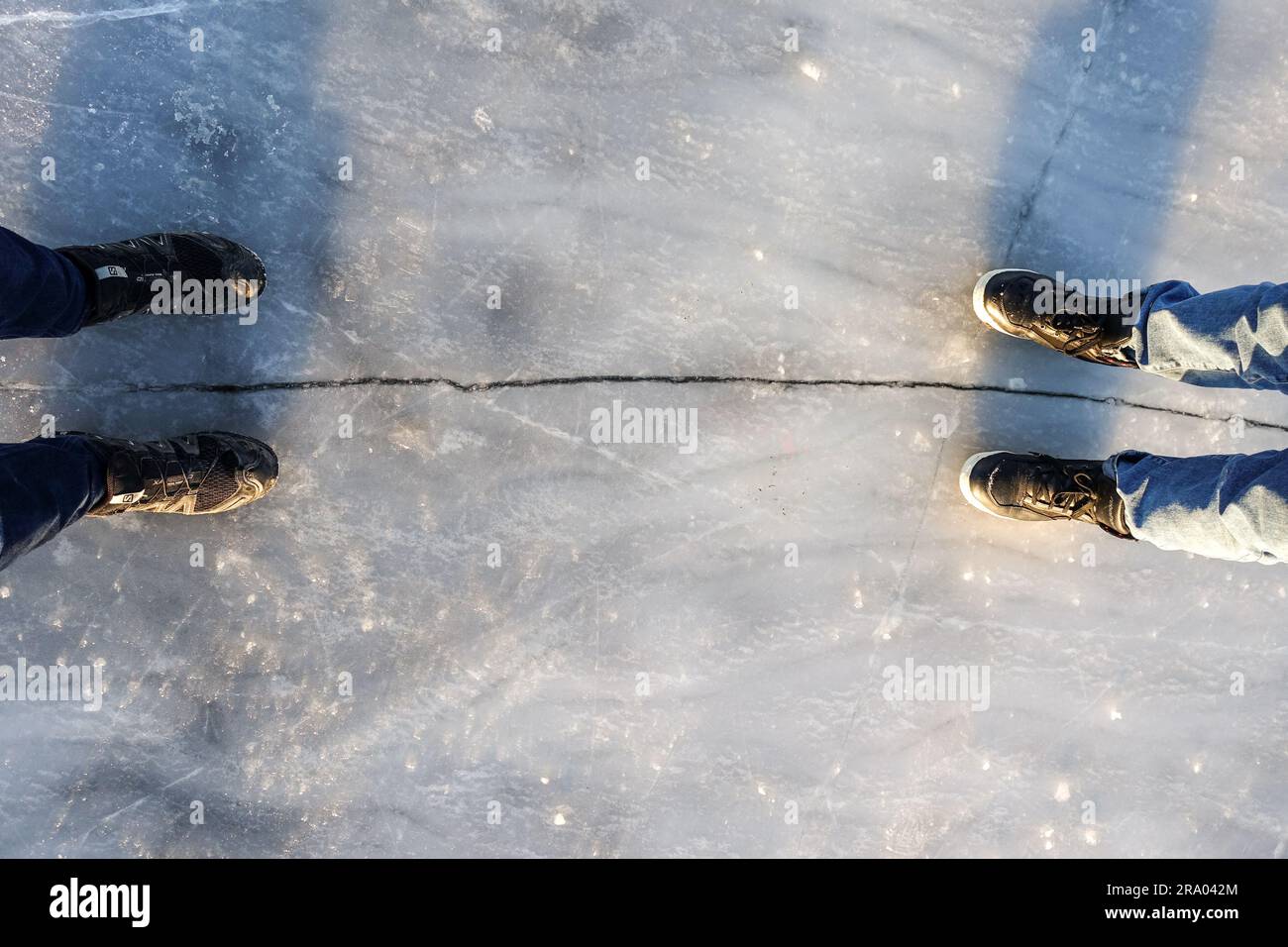 Cracked ice and feet on each side of the crack, taken on a lake in ...