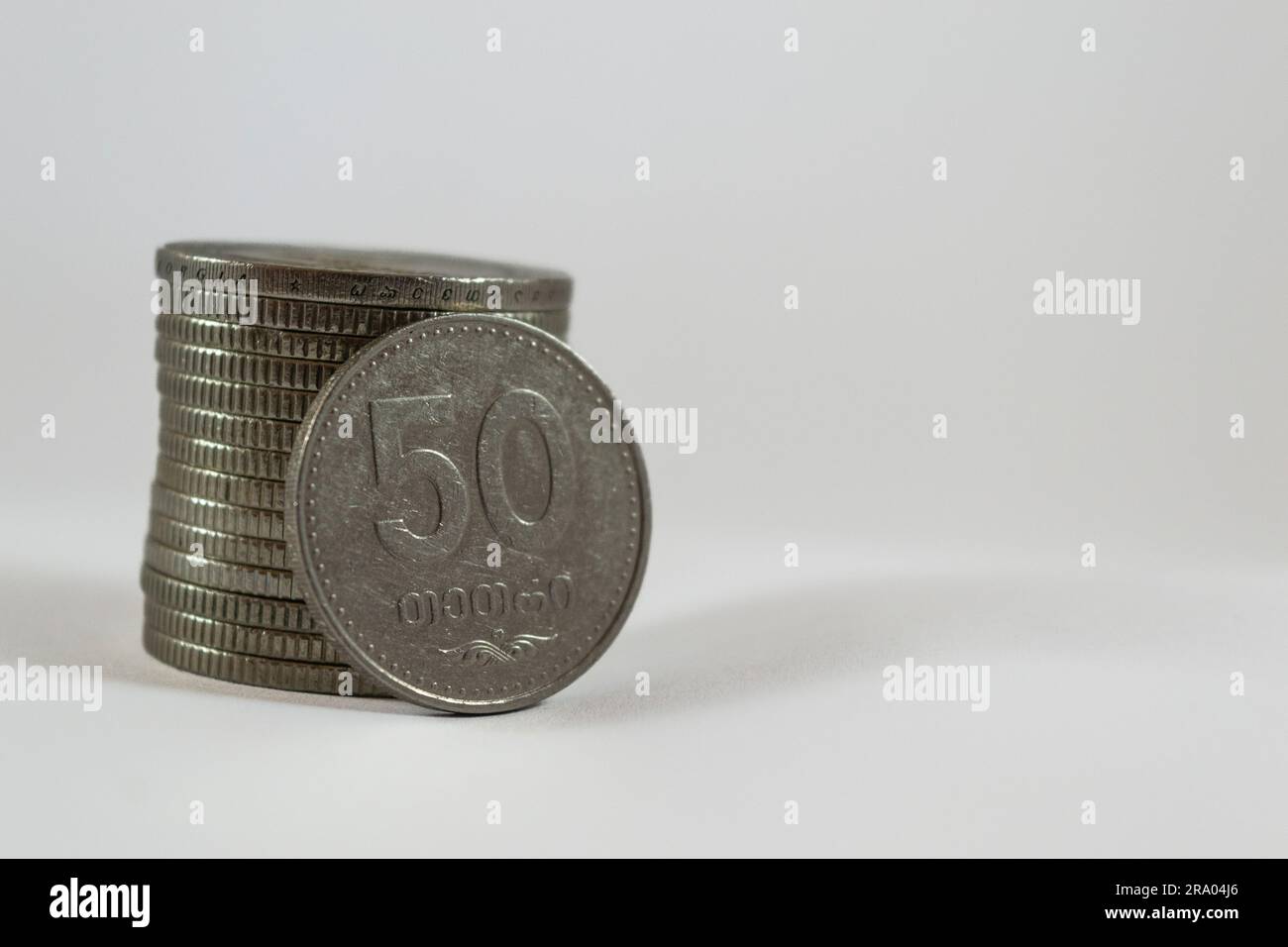 A stack of Georgian Lari coins with a 50 Lari coin leaning on it on a ...