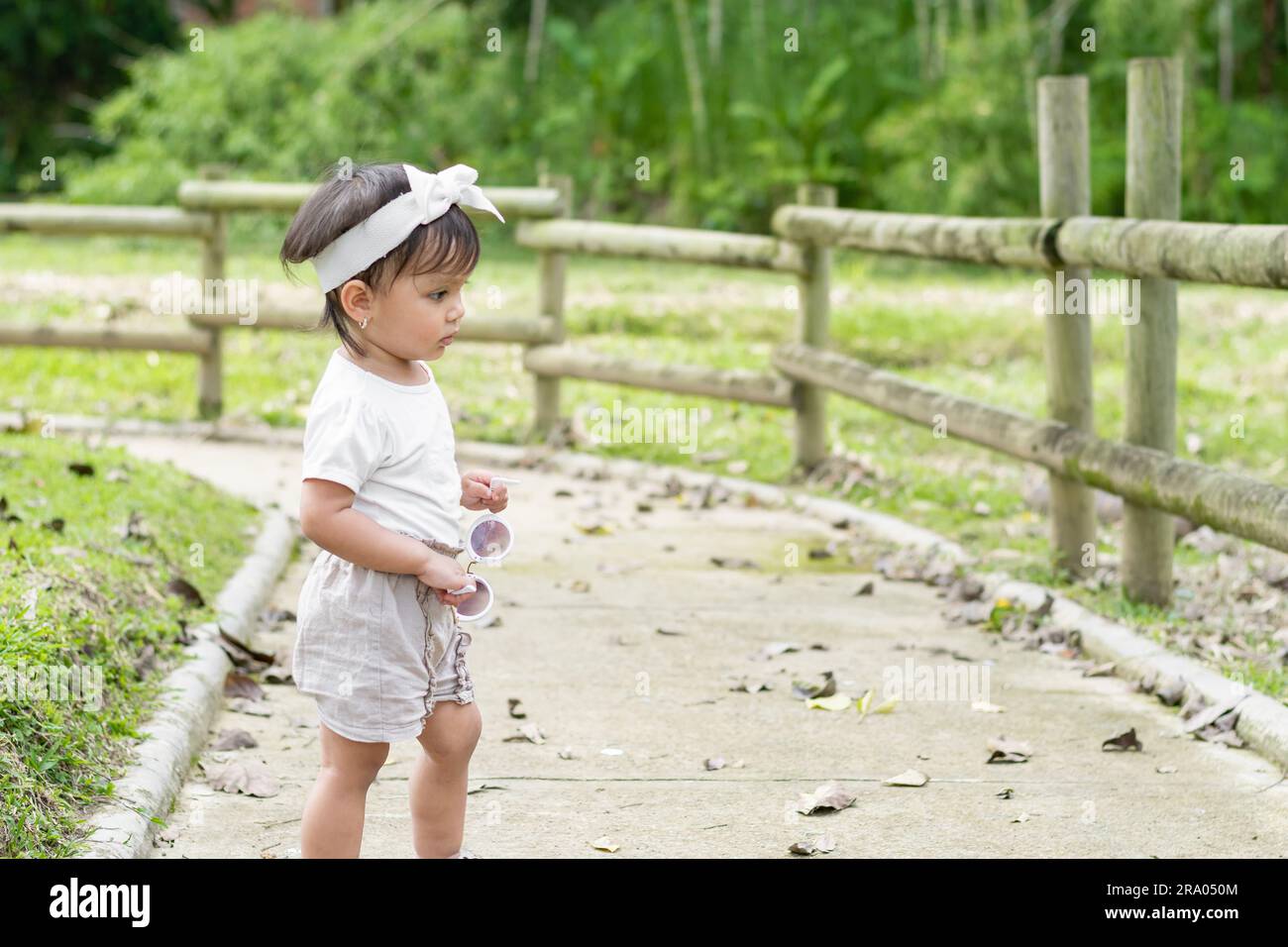 little brunette latina girl, standing in the middle of the path with a ...