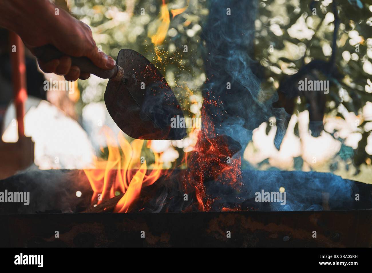 Hand adding coil on grill fire Stock Photo - Alamy