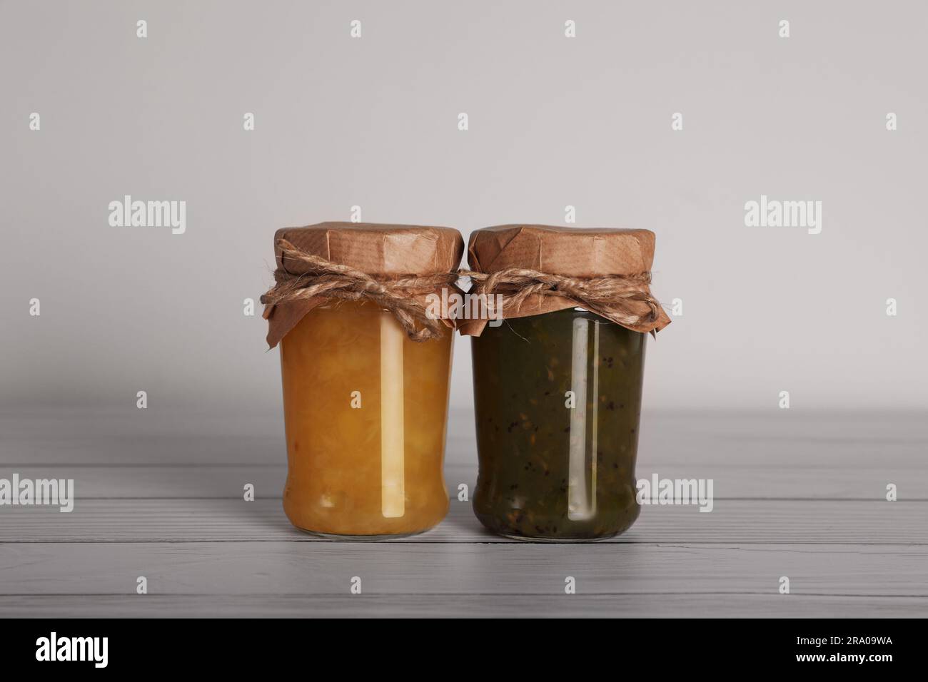Jars with preserved fruit jams on white wooden table Stock Photo - Alamy