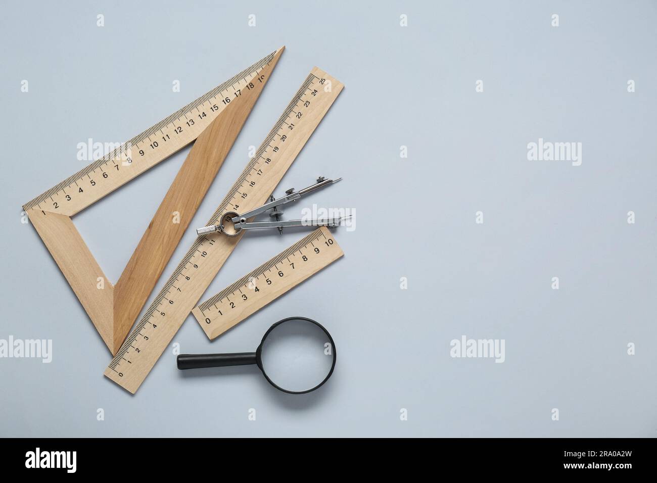 Different rulers, magnifying glass and compass on light grey background ...