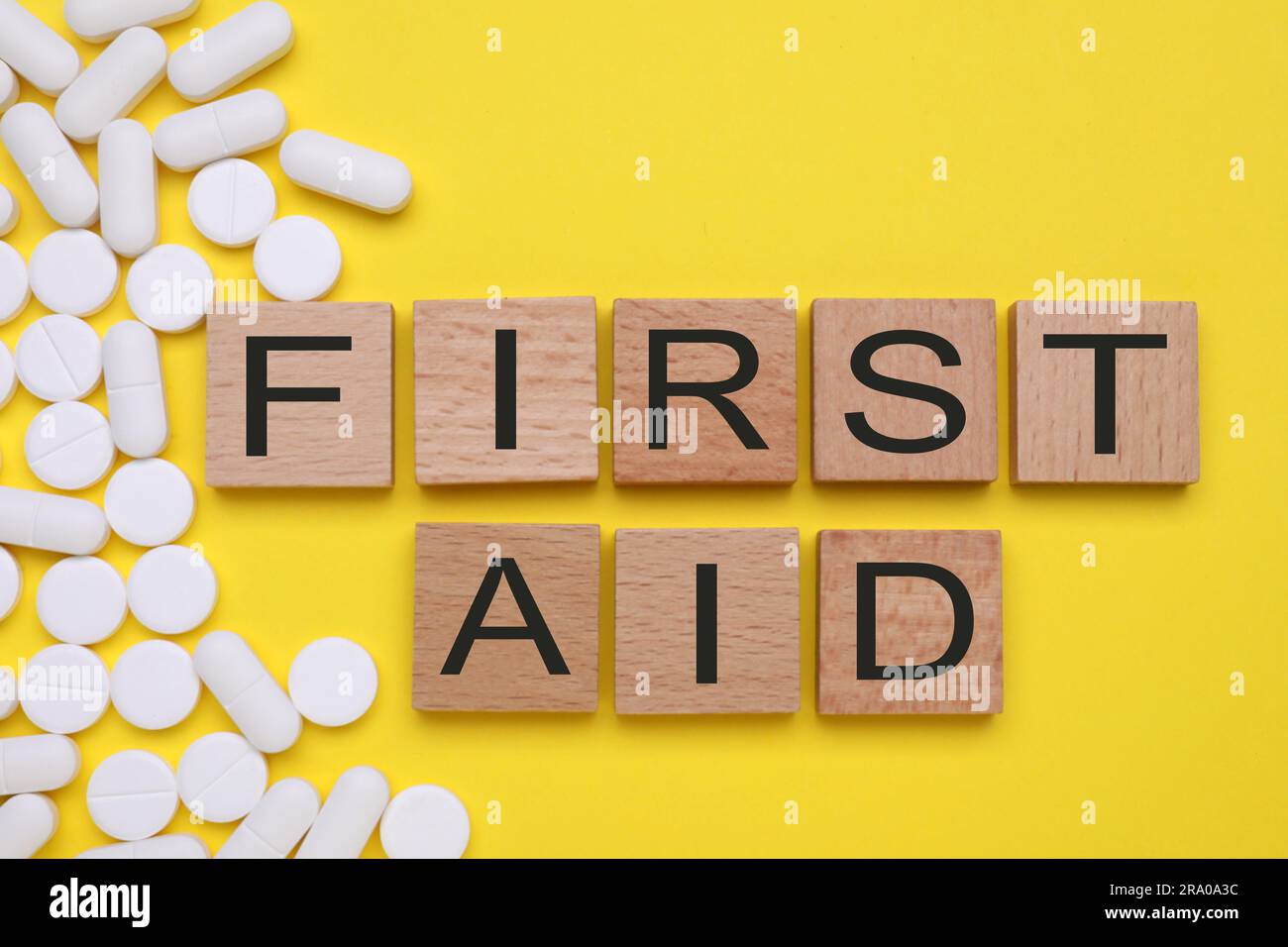 Words First Aid made of wooden cubes and pills on yellow background ...