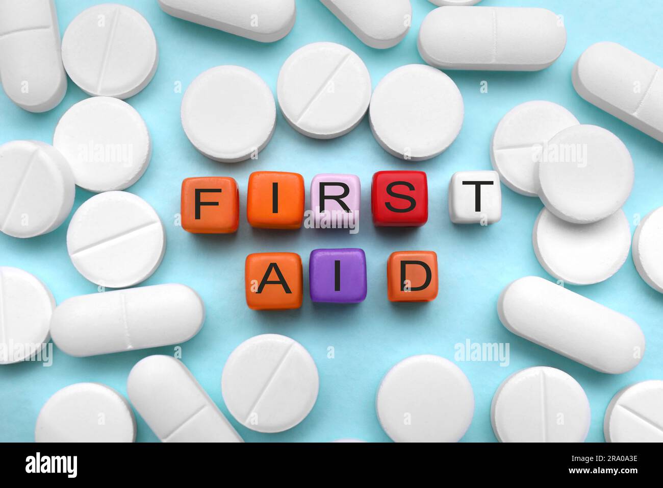Colorful cubes with words First Aid and pills on light blue background ...