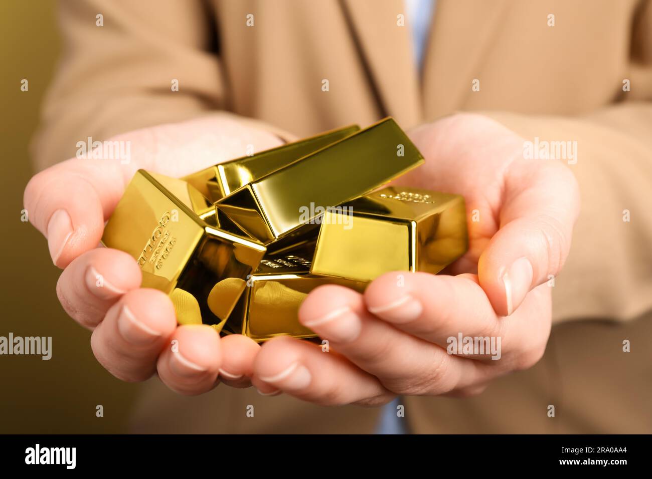 Woman holding shiny gold bars on yellow background, closeup Stock Photo - Alamy