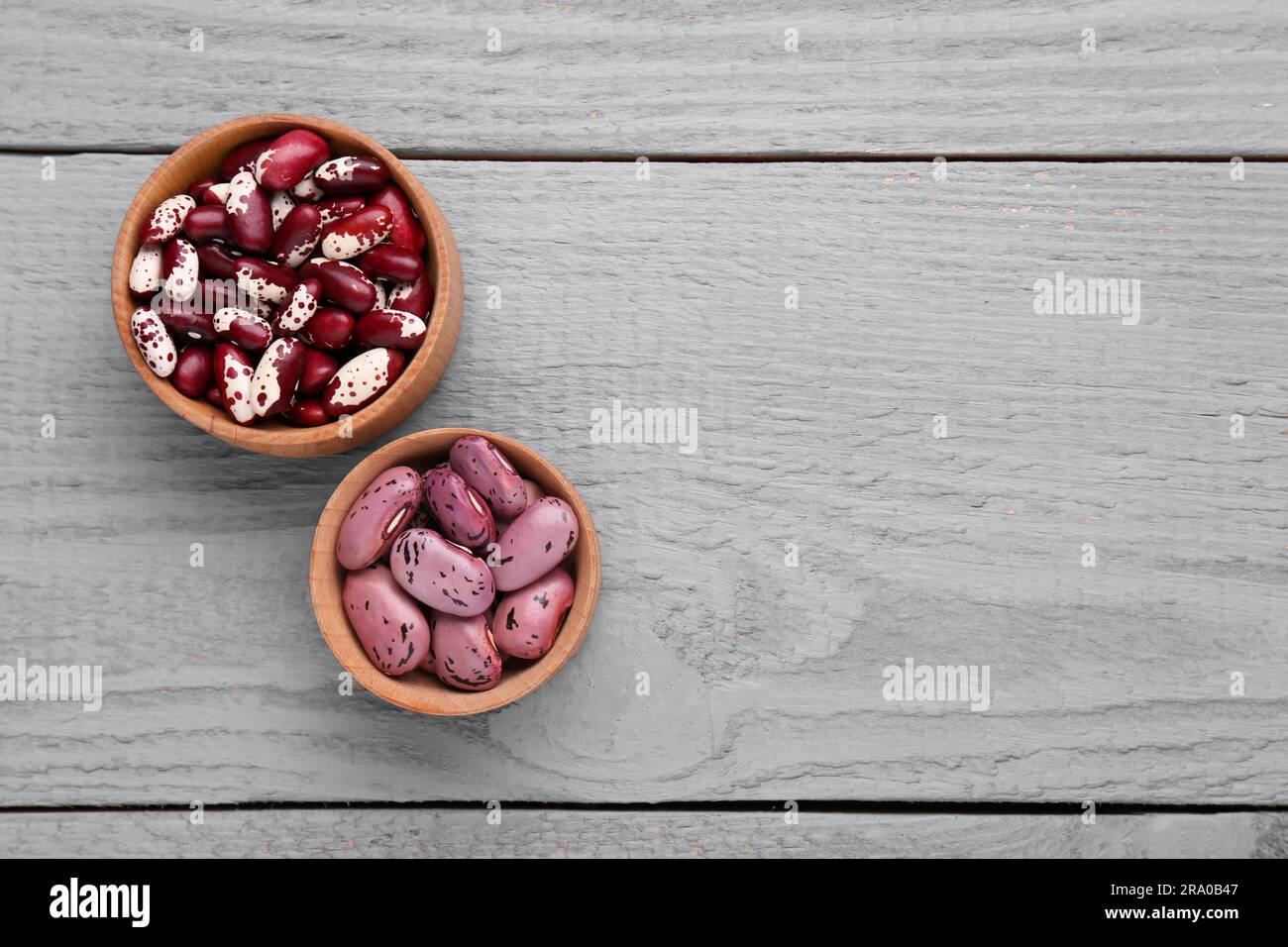 Different kinds of dry kidney beans on grey wooden table, flat lay ...