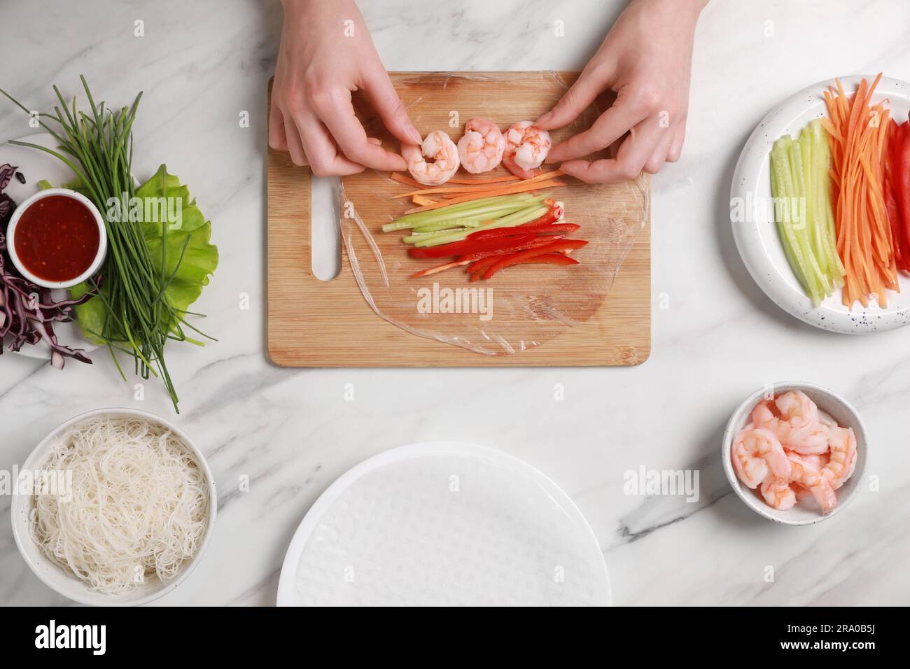 Making delicious spring rolls. Woman wrapping fresh vegetables and ...