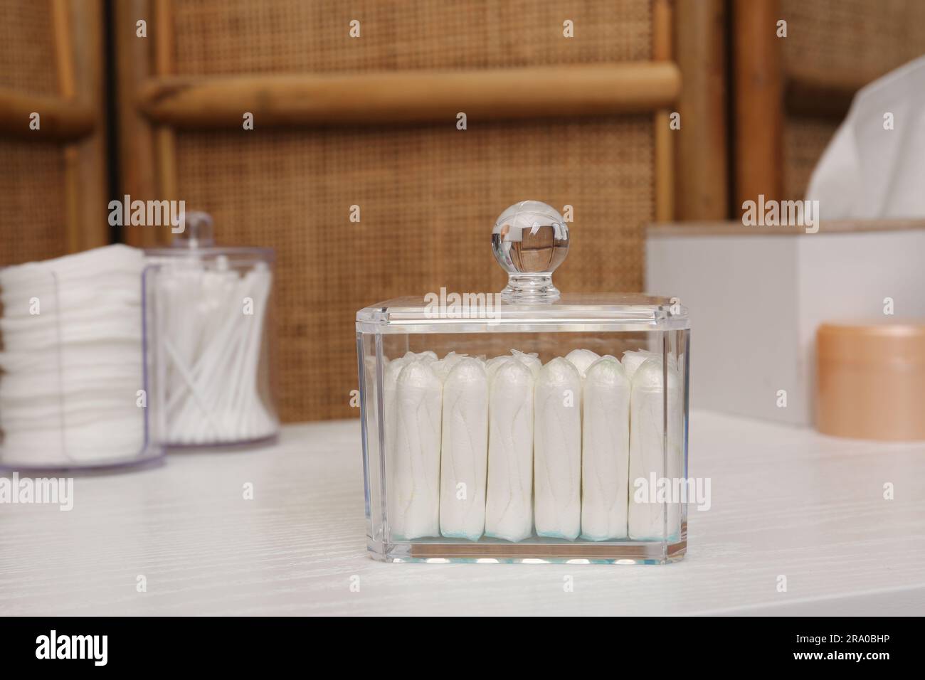 Glass holder with many tampons on white table. Menstrual hygienic ...