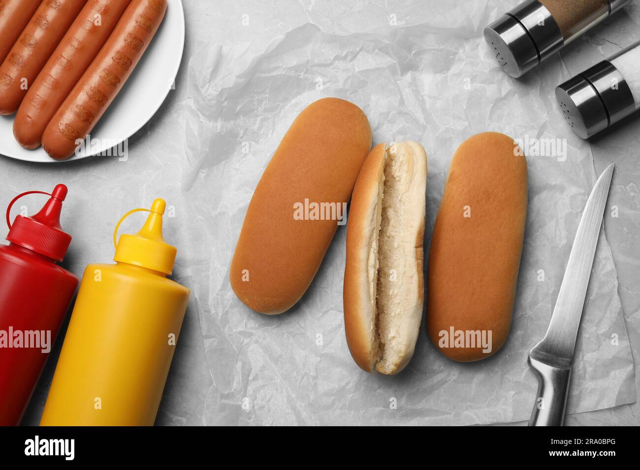 Different tasty ingredients for hot dog on light grey marble table ...