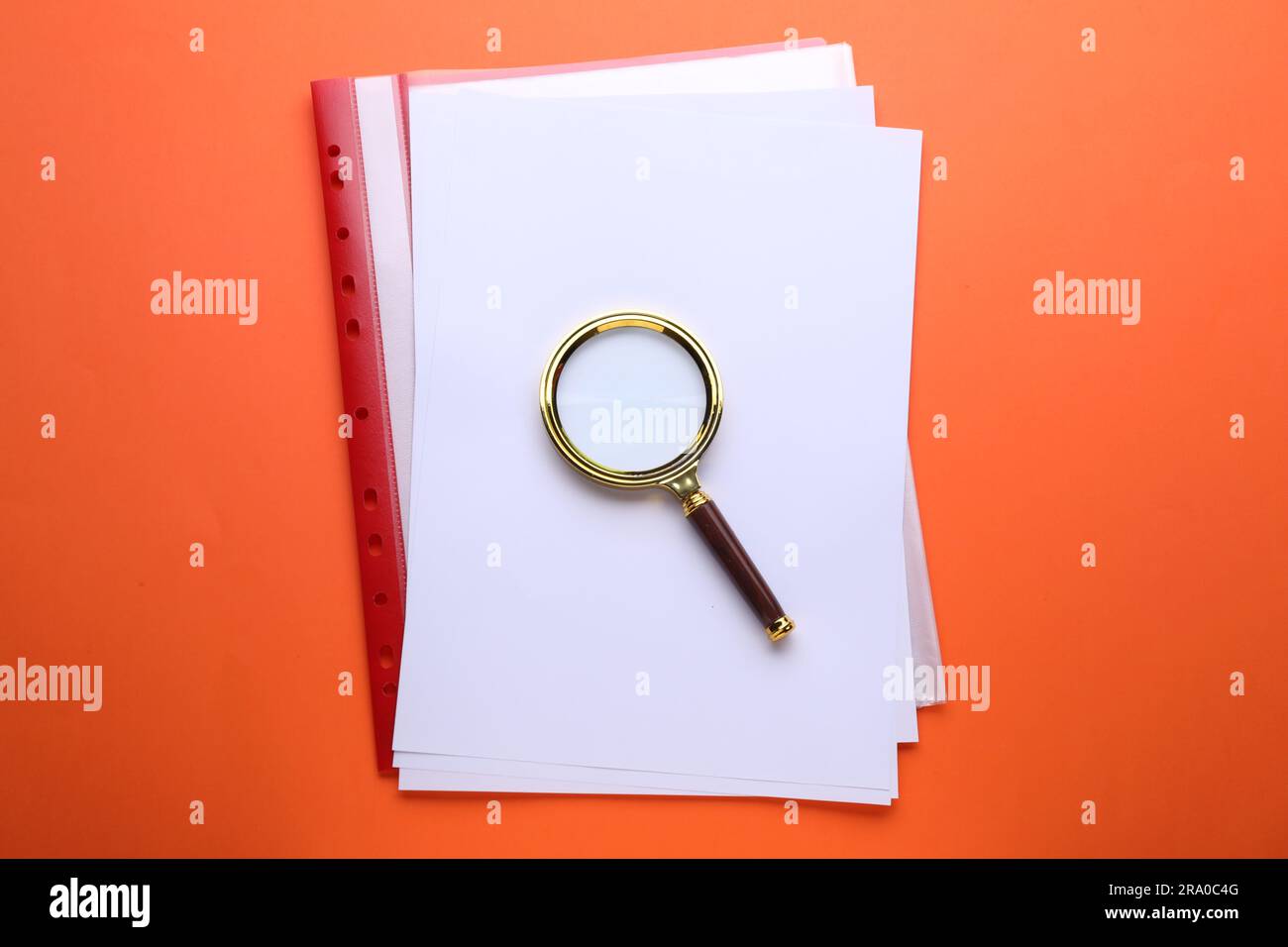 Magnifying glass and folder with paper sheets on orange background, top ...