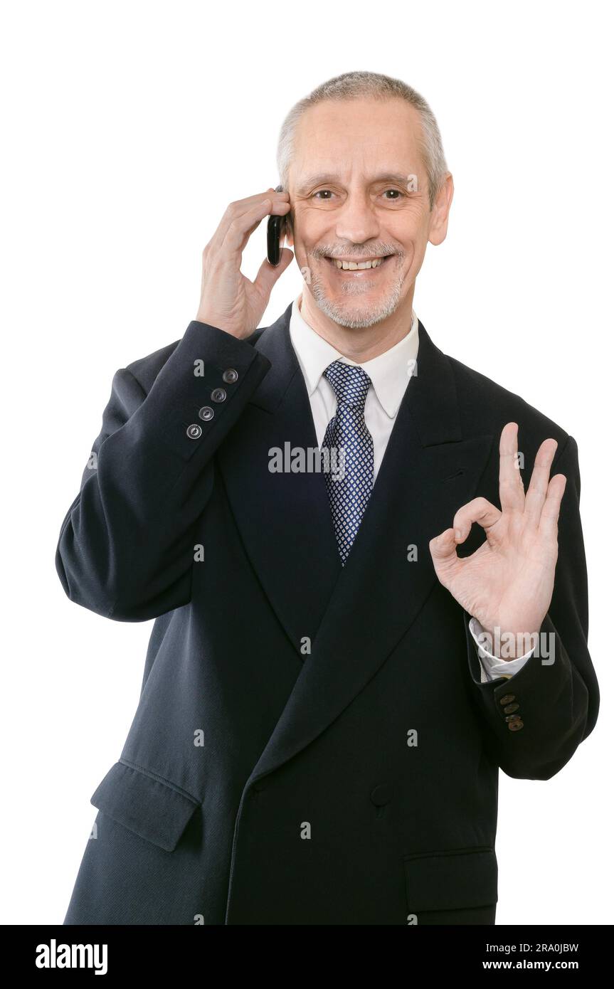 An amiable businessman smiling on mobile phone and showing the okay ...