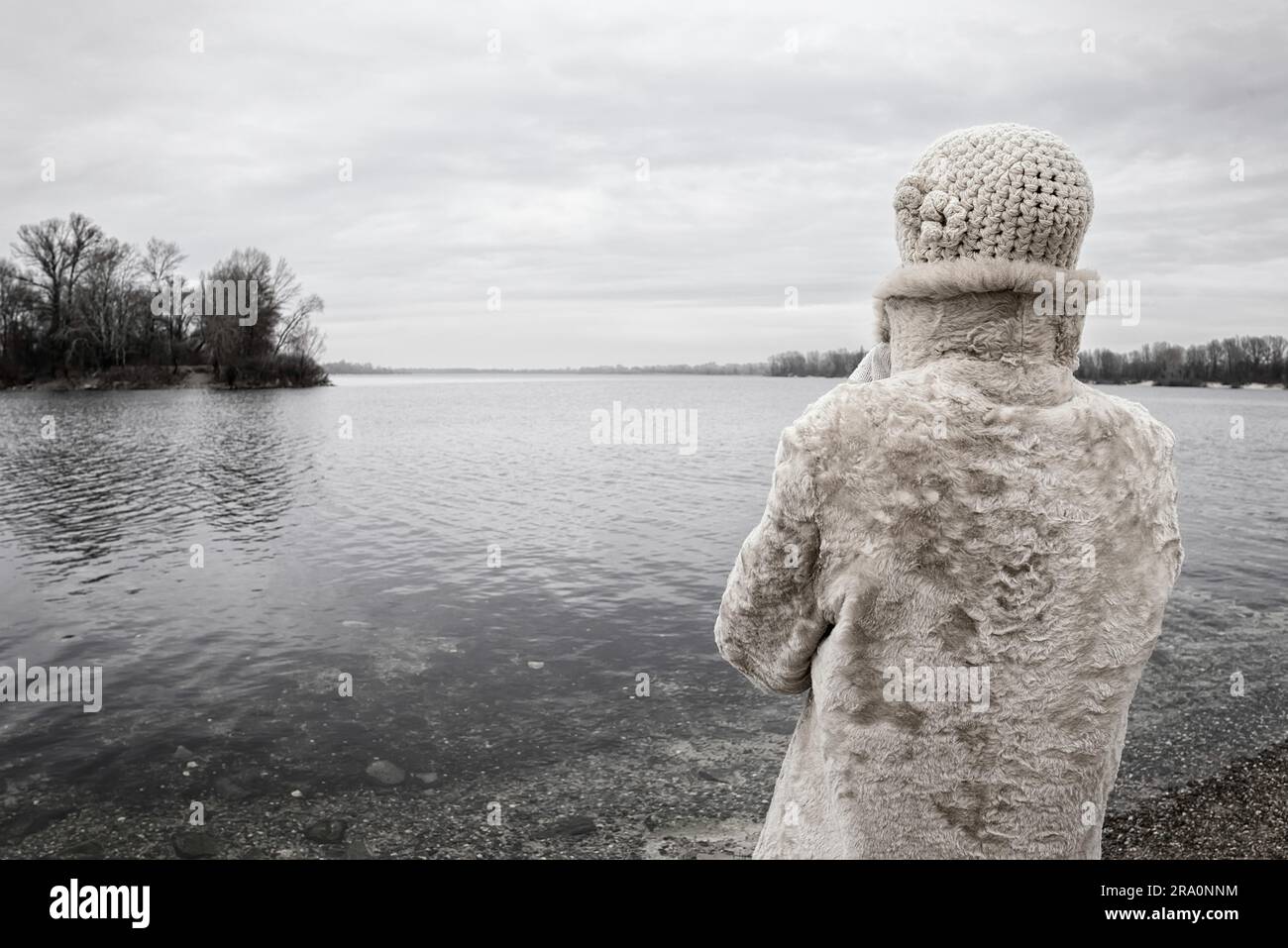 A woman with a wool cap and a fur coat is looking at the river during a ...