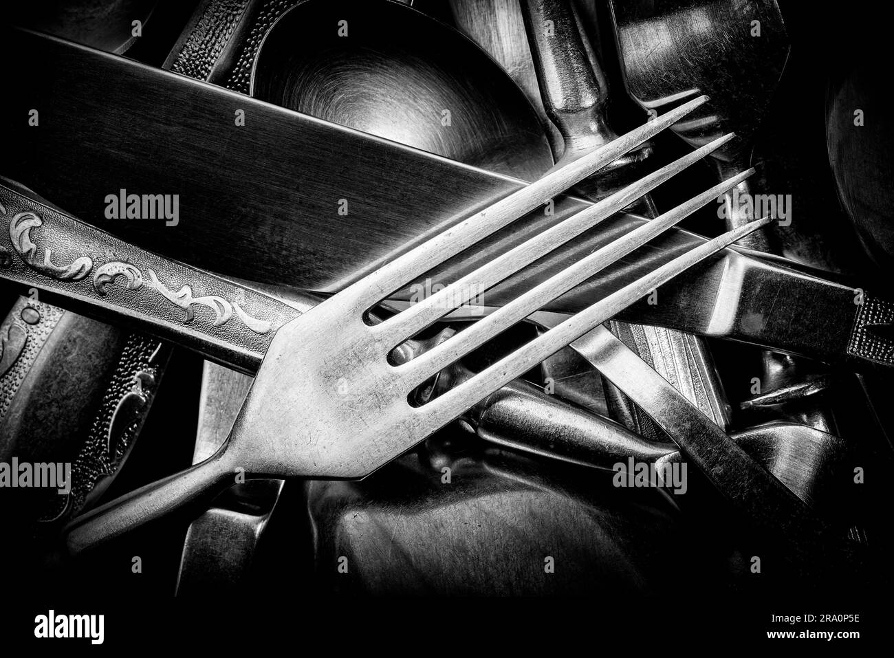 Abstract black and white photo of mixed silver forks, spoons and knives ...