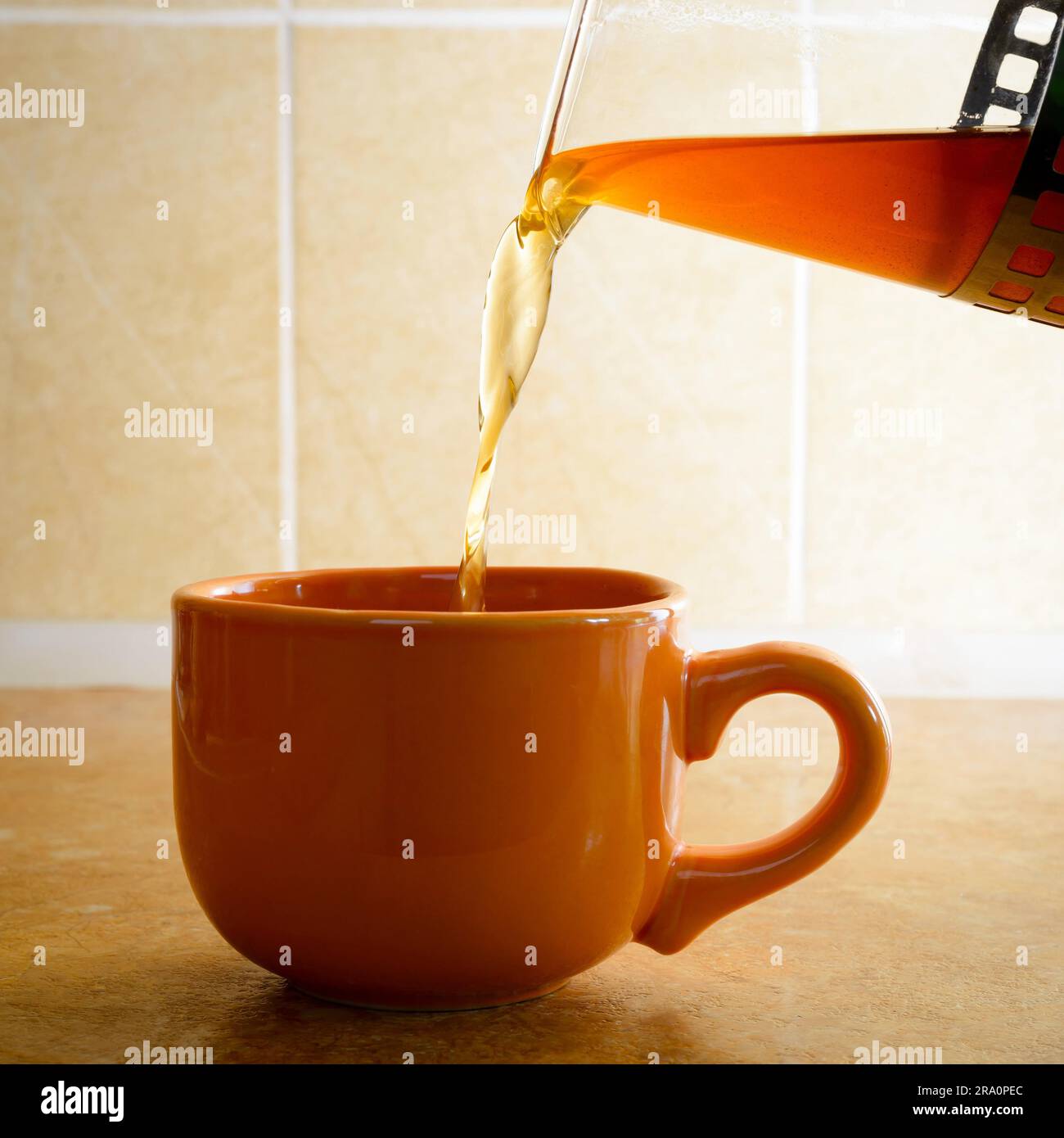 Pouring hot tea in an orange porcelain cup, in the kitchen Stock Photo ...