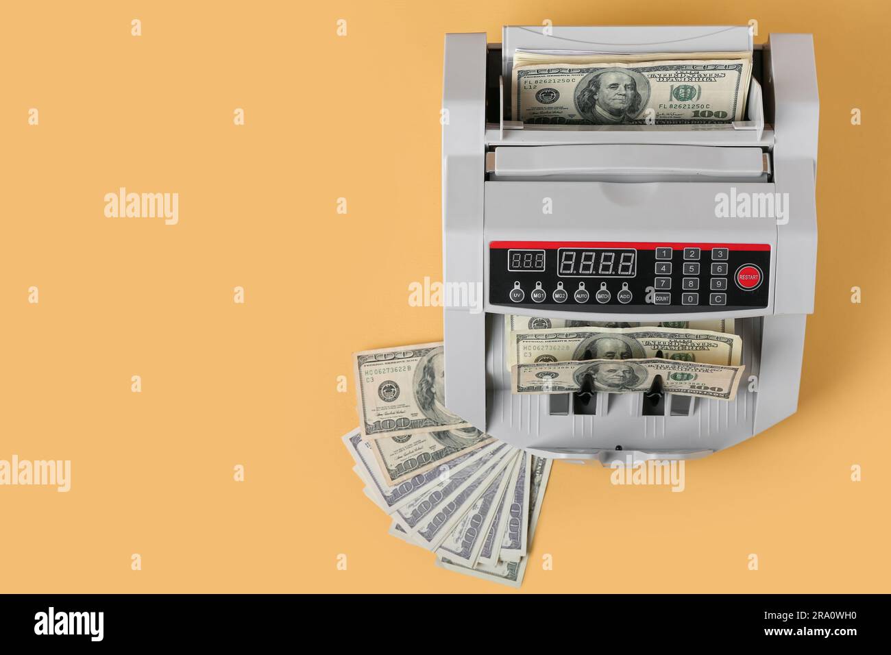 Modern cash counting machine with dollar banknotes on yellow background ...