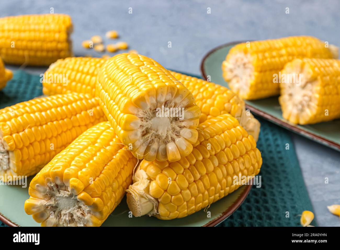 Plates with cut fresh corn cobs on blue background Stock Photo - Alamy