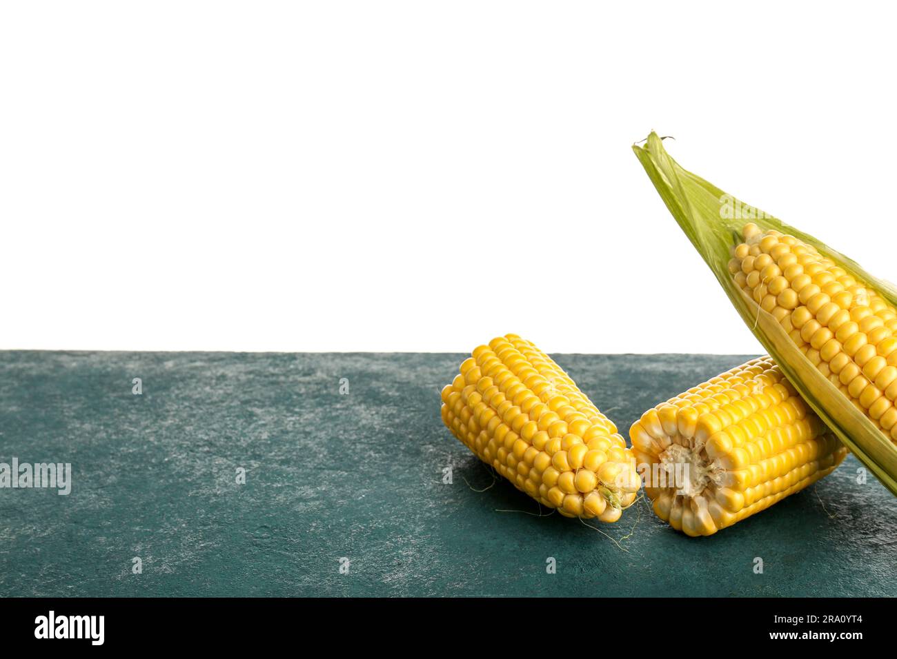 Fresh corn cobs on blue table against white background Stock Photo - Alamy