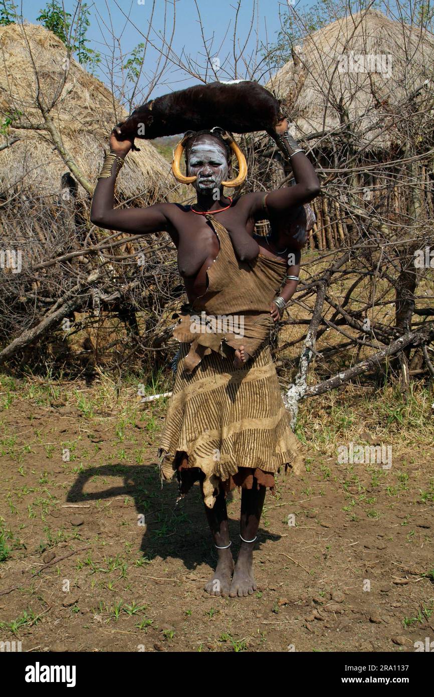 Woman with child, Mursi tribe, warthog teeth as headdress, Mago ...