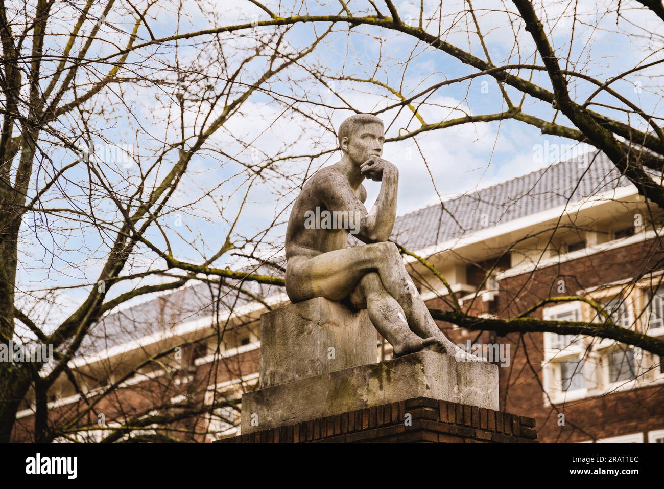 a statue sitting on top of a stone block in front of a brick building ...