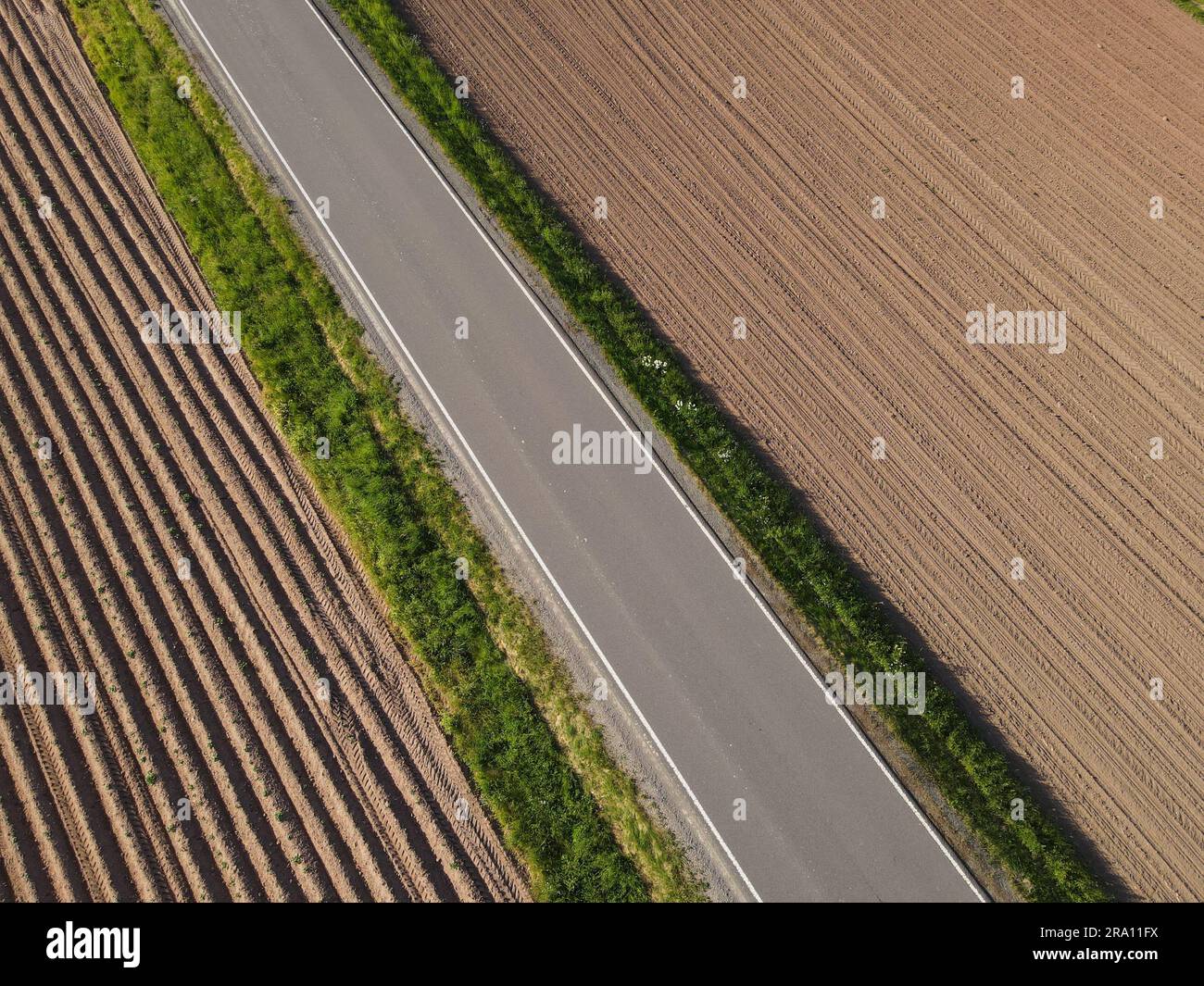 View from above of a asphalt road between plowed agriculture land with ...