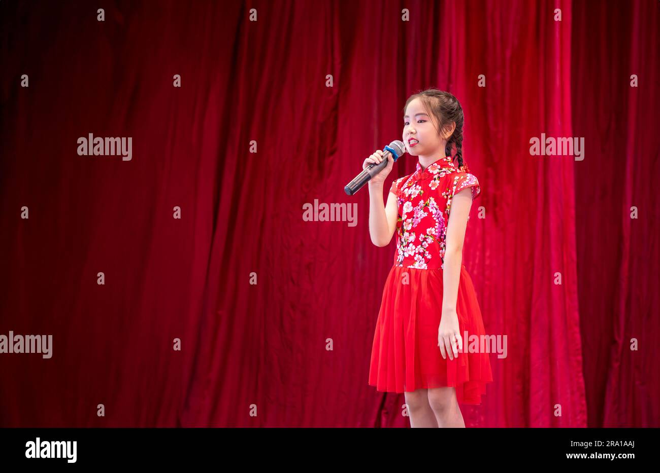 The Asian kid girl sing a song on stage at her school activity day ...