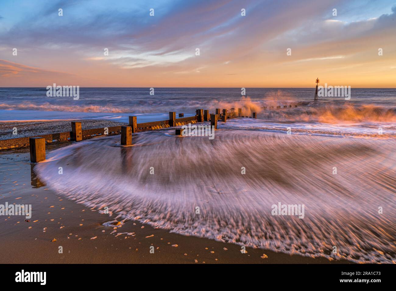 An idyllic wooden dock leading into the ocean waves at a peaceful ...
