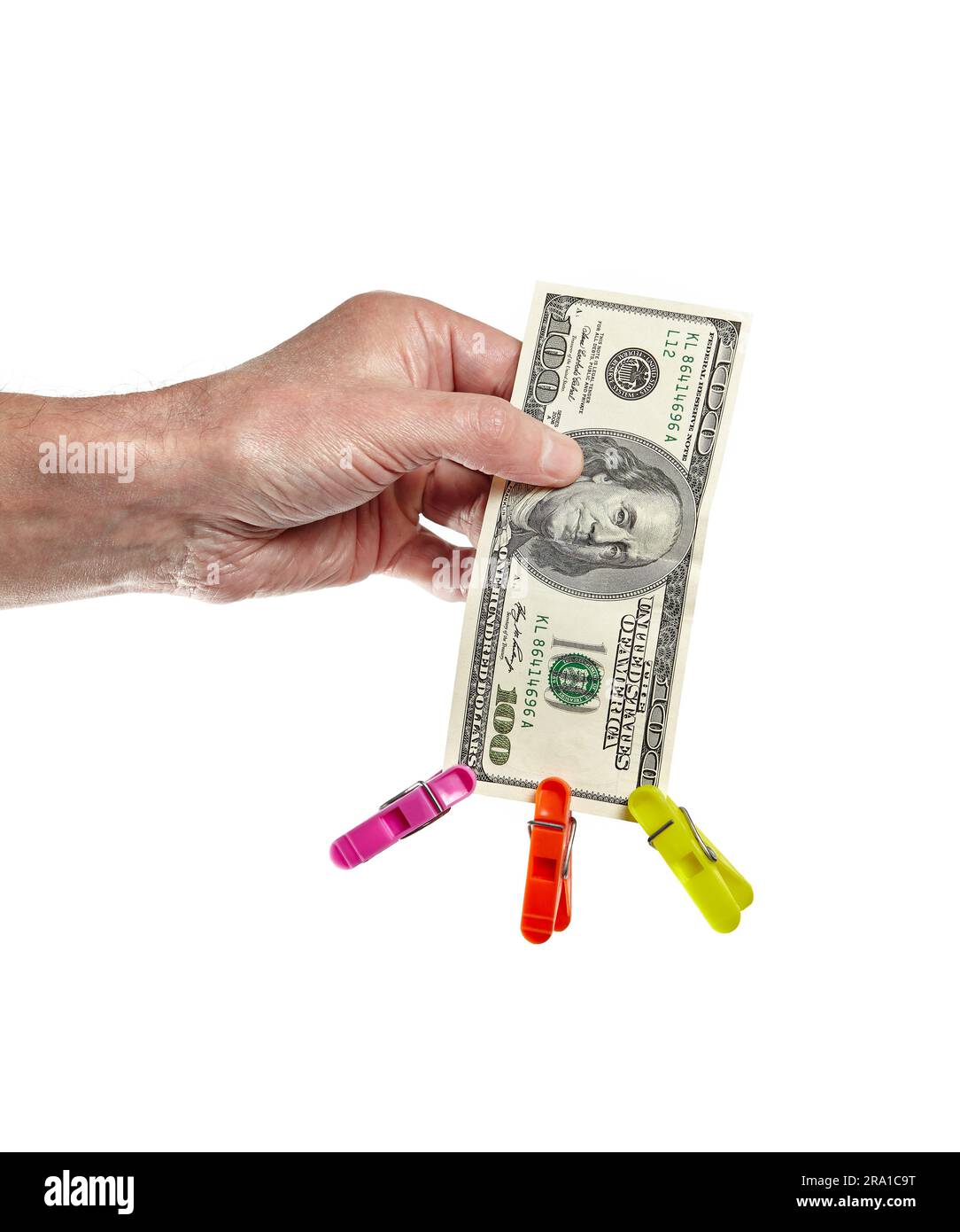 Men's hand holding 100 dollar bill with clothes pins isolated on white ...