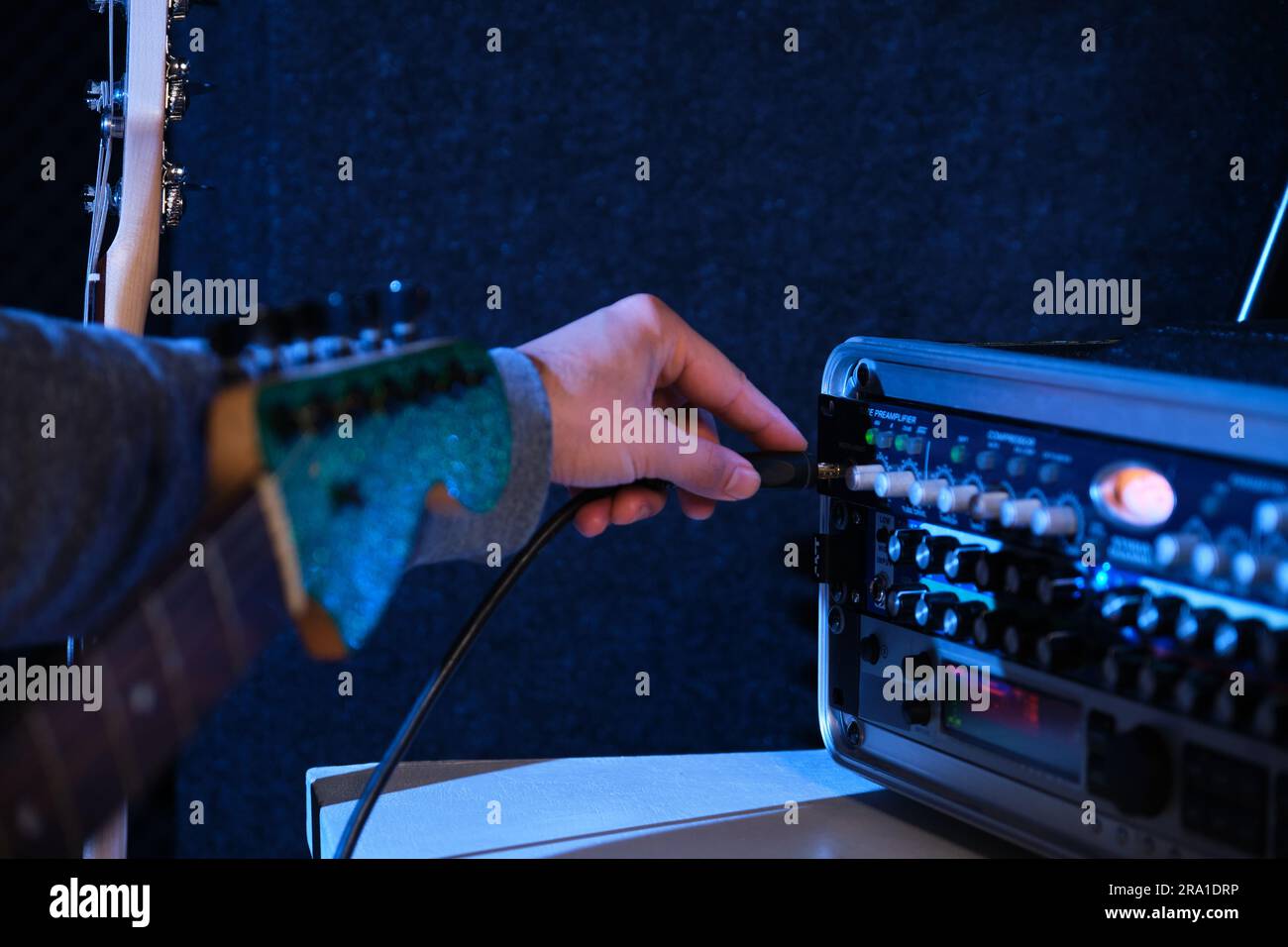 Close up of a musician hand connecting his electric guitar to a mixing ...
