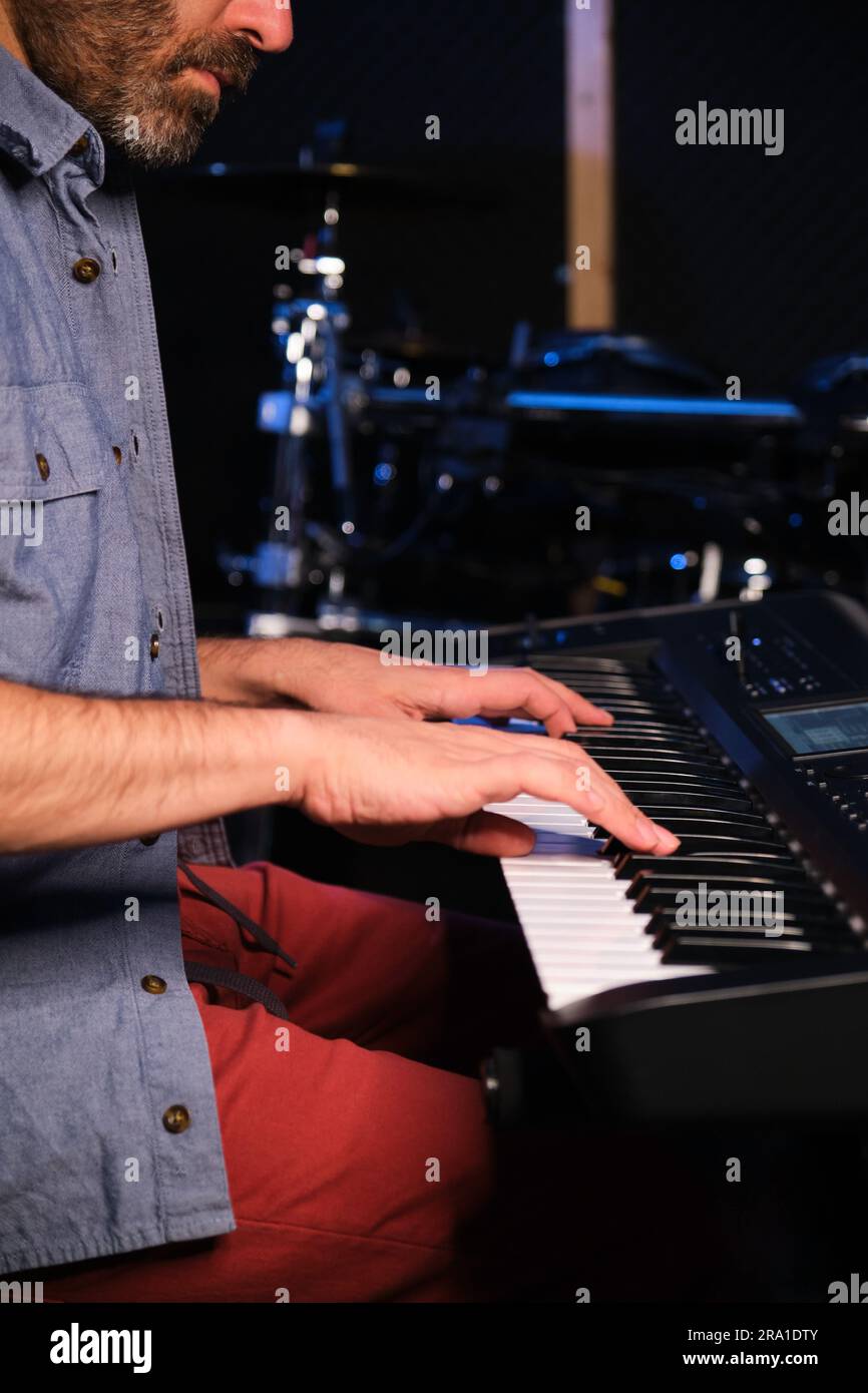 Musician man playing keyboard synthesizer piano in a recording studio ...