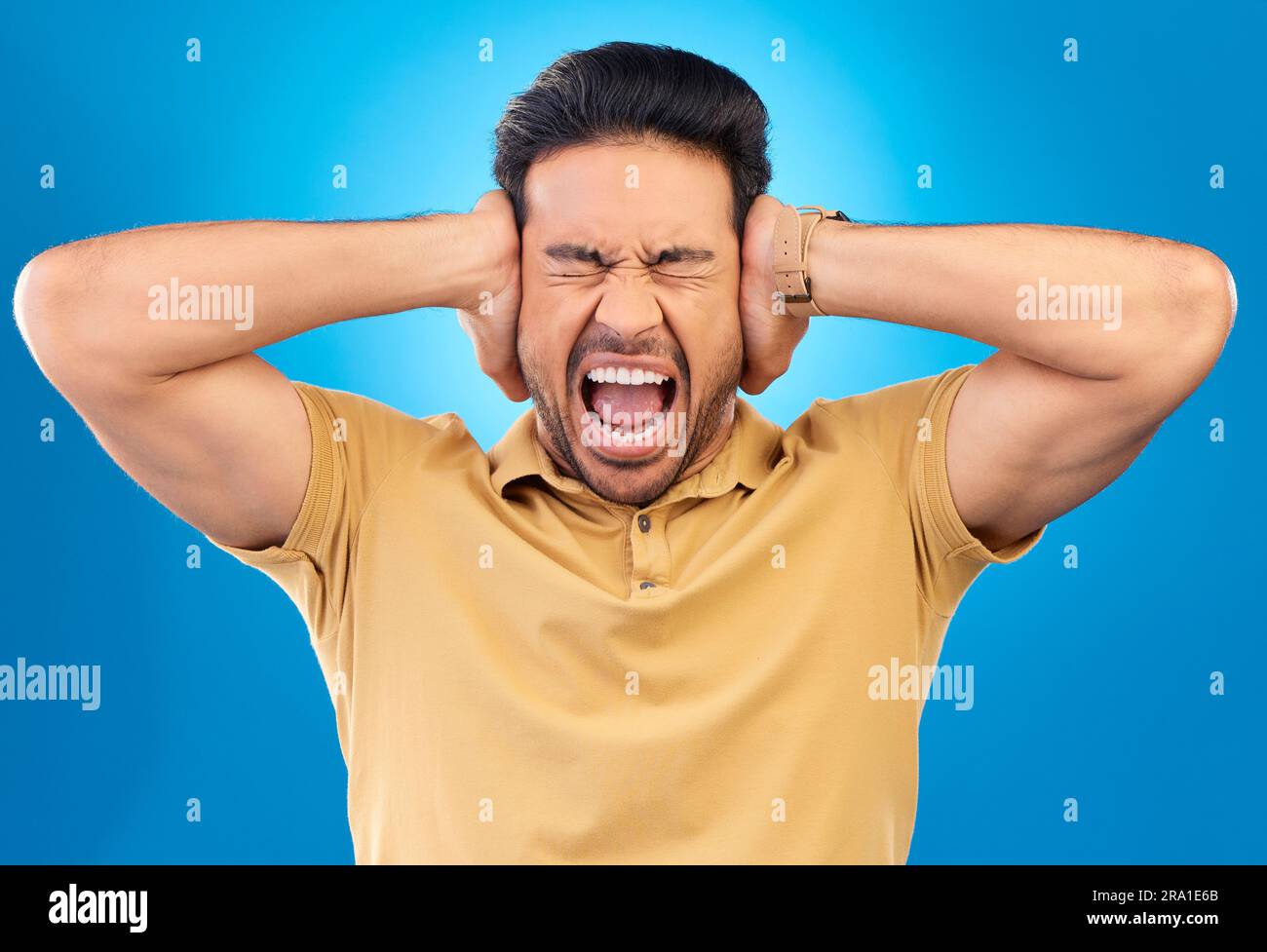 Man covering his ears while screaming in a studio for angry, upset or ...