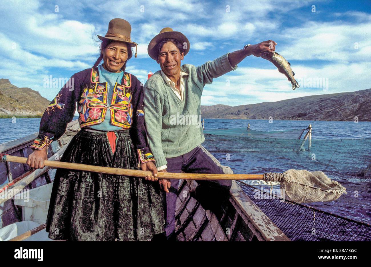 Peru, Couple in a rowing boat and owners of a fishfarm, at work on ...