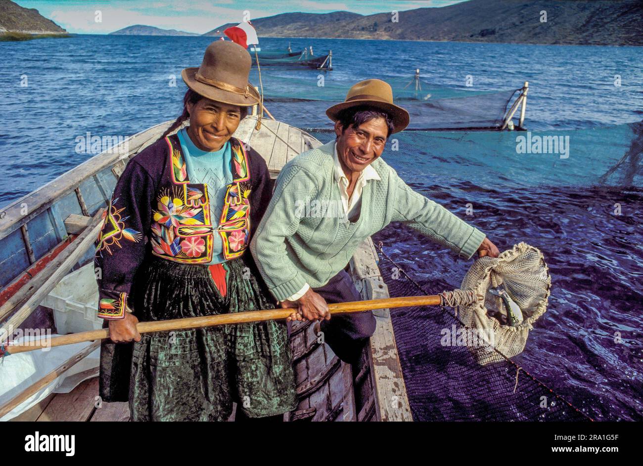 Peru, Couple in a rowing boat and owners of a fishfarm, at work on ...
