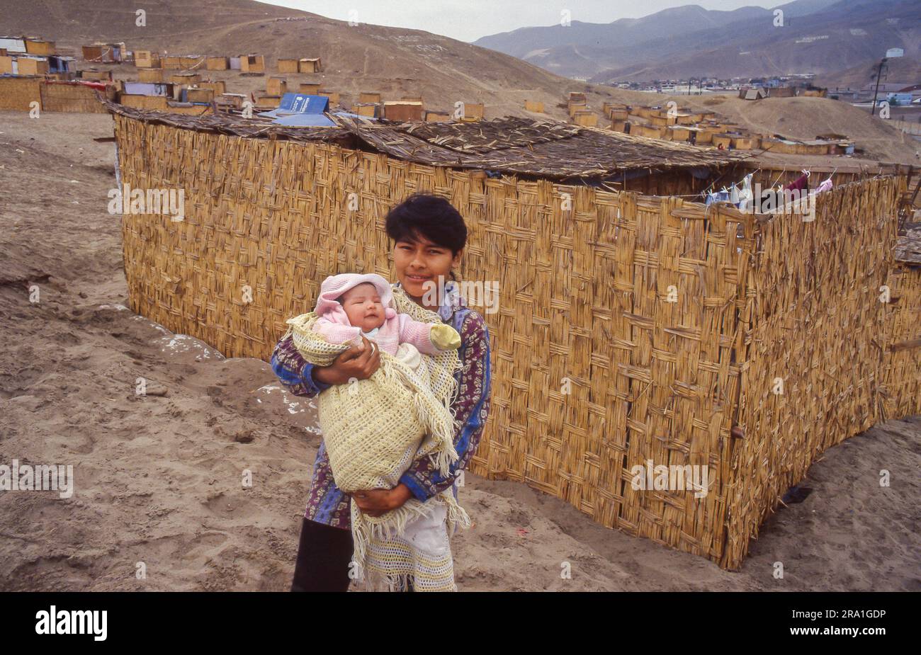 Peru - Mother with her baby in front of her hut, made of reed, in a ...
