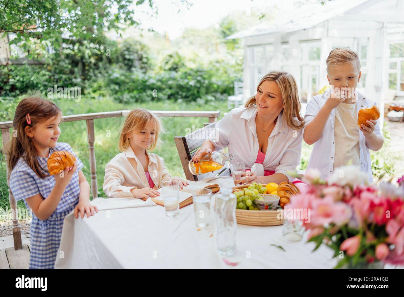 Young mother and three children are having lunch on terrace of house ...