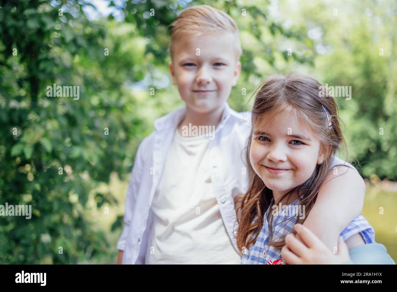 Two cute kids in casual clothes hug and pose for camera. Brother and ...