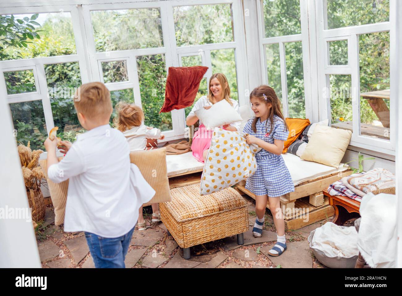 Big cheerful family is having fun in glass gazebo in garden. Three ...