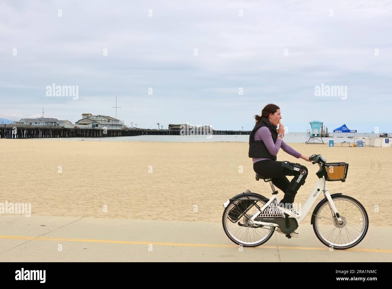 Cyclist riding along a cycle path next to an empty beach on a cold May ...