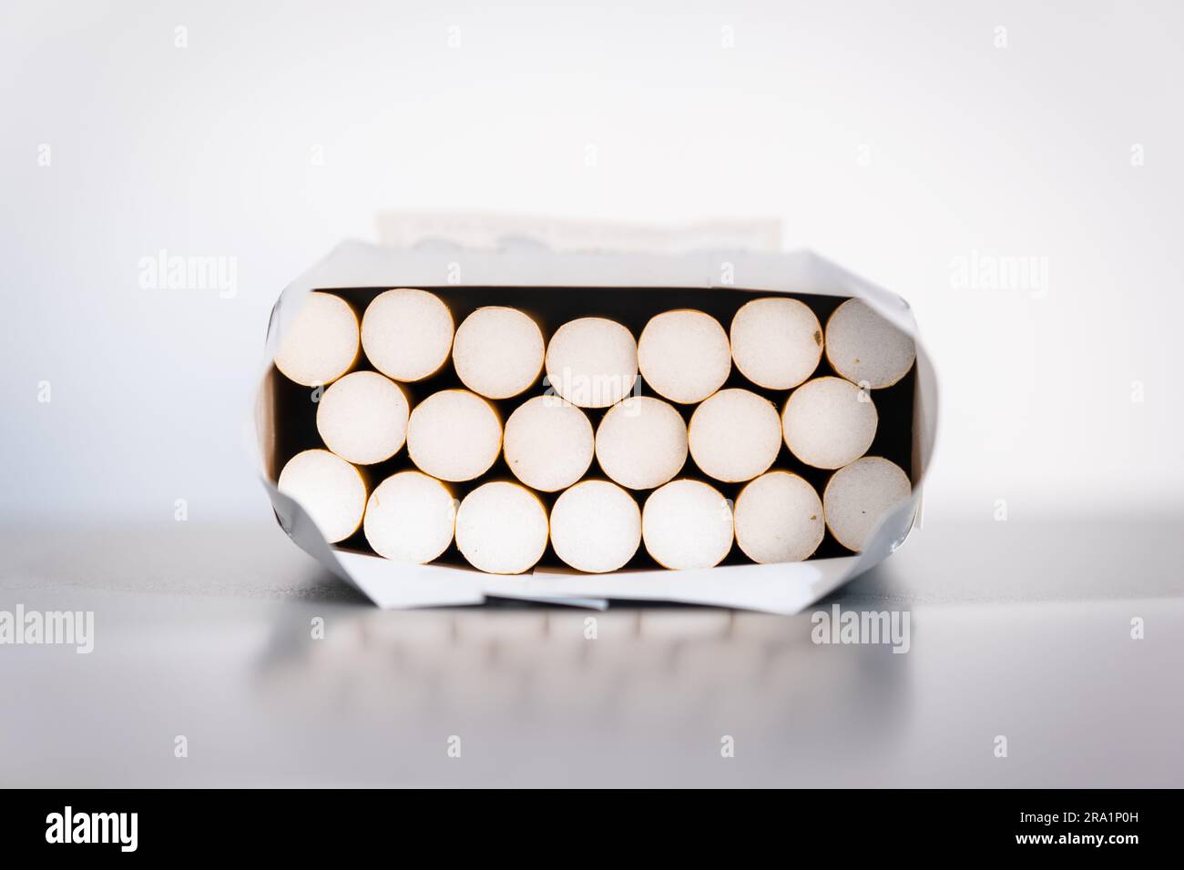 Full opened pack of cigarettes is placed on the glossy surface, white ...